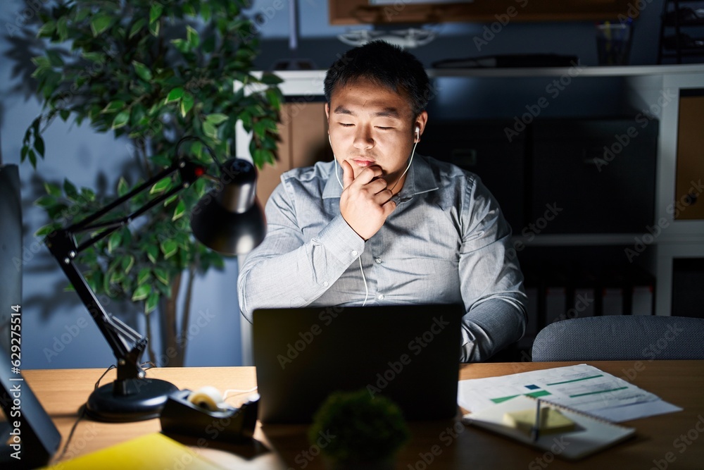 Young chinese man working using computer laptop at night looking ...