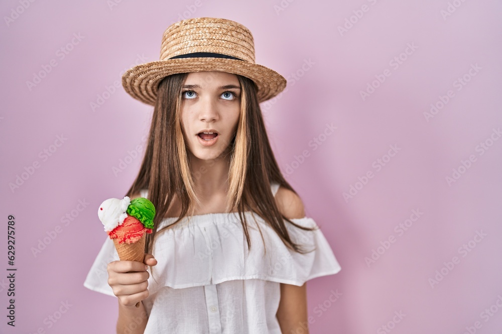 Teenager girl holding ice cream angry and mad screaming frustrated and ...