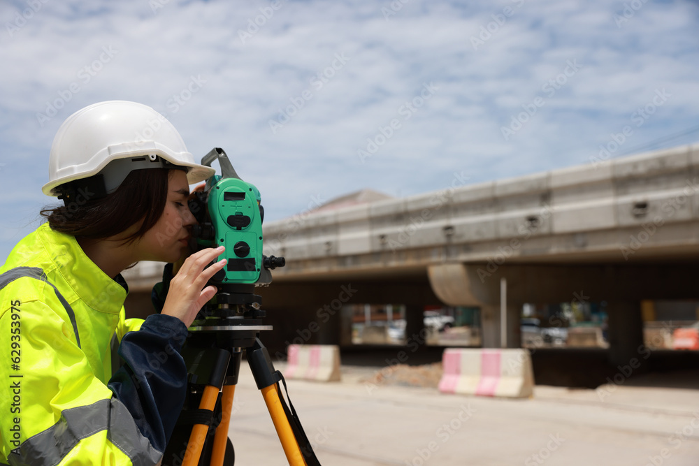 Site female engineer operating her instrument during roadworks. Builder ...