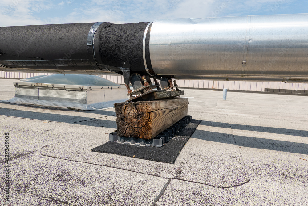 Roof mounted industrial insulated HVAC pipes on gray roof and wooden ...