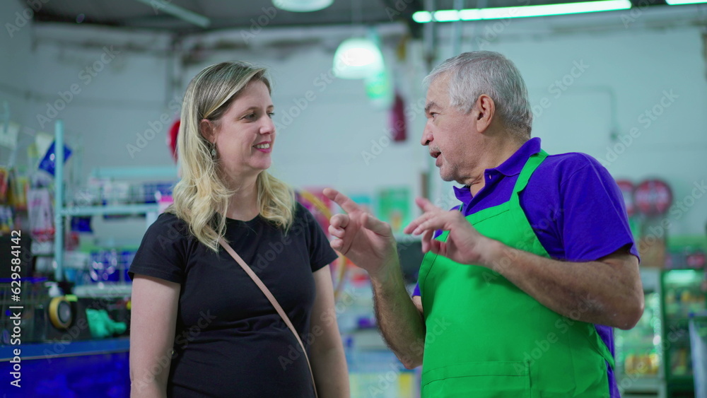 Senior employee of Grocery Store speaking with a female customer inside ...