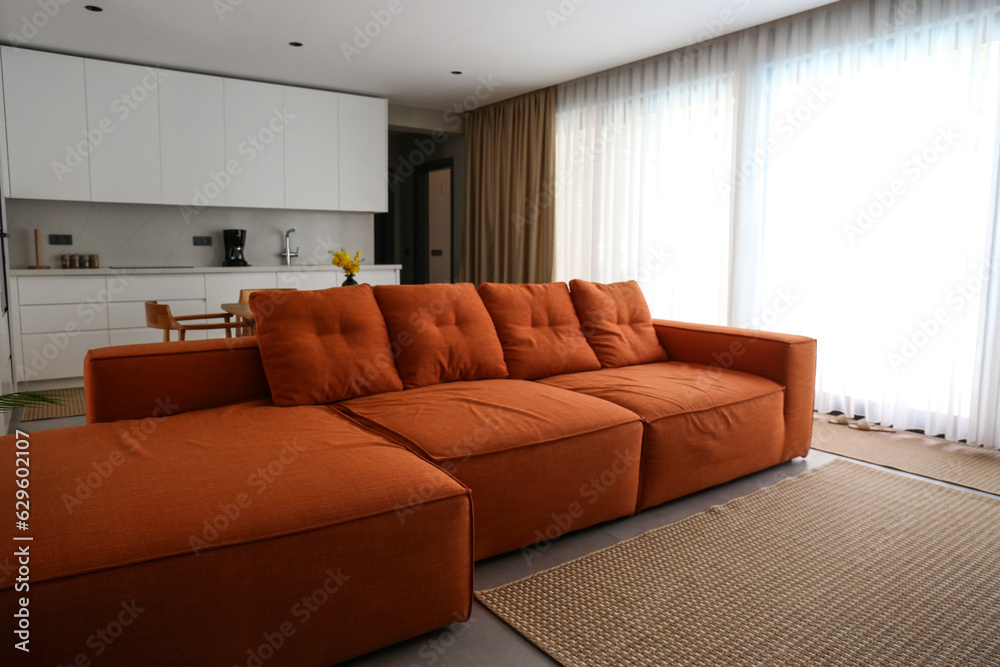 Open plan living room with orange textile couch and white cupboard ...