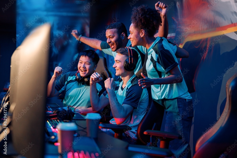 Multiracial cybersport gamers expressing success while raising hands up ...