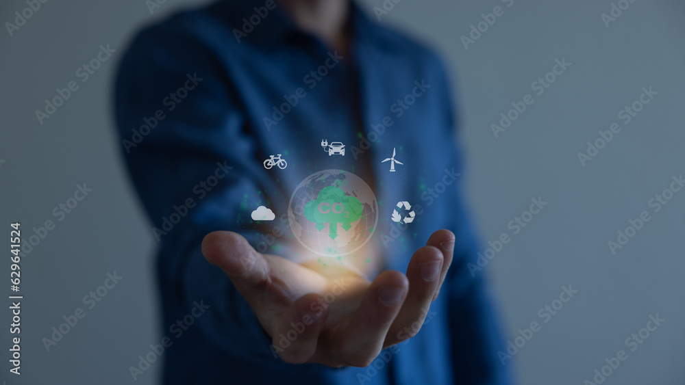 Hand holding virtual Global with CO2 reducing icon for concept of decrease carbon dioxide ...