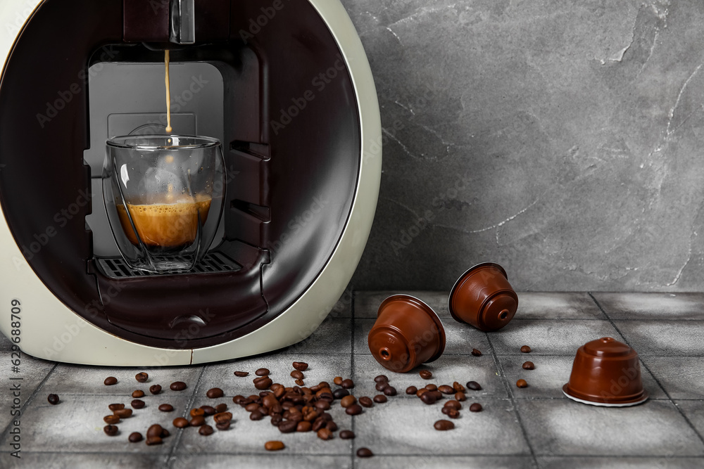 Modern capsule coffee maker with dripping espresso, cup, pods and beans ...