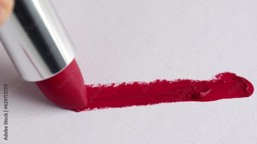 A woman's hand with red lipstick making a mark on a white background ...