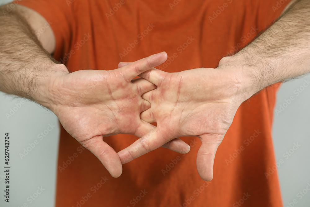 Man cracking his knuckles on light grey background, closeup. Bad habit ...