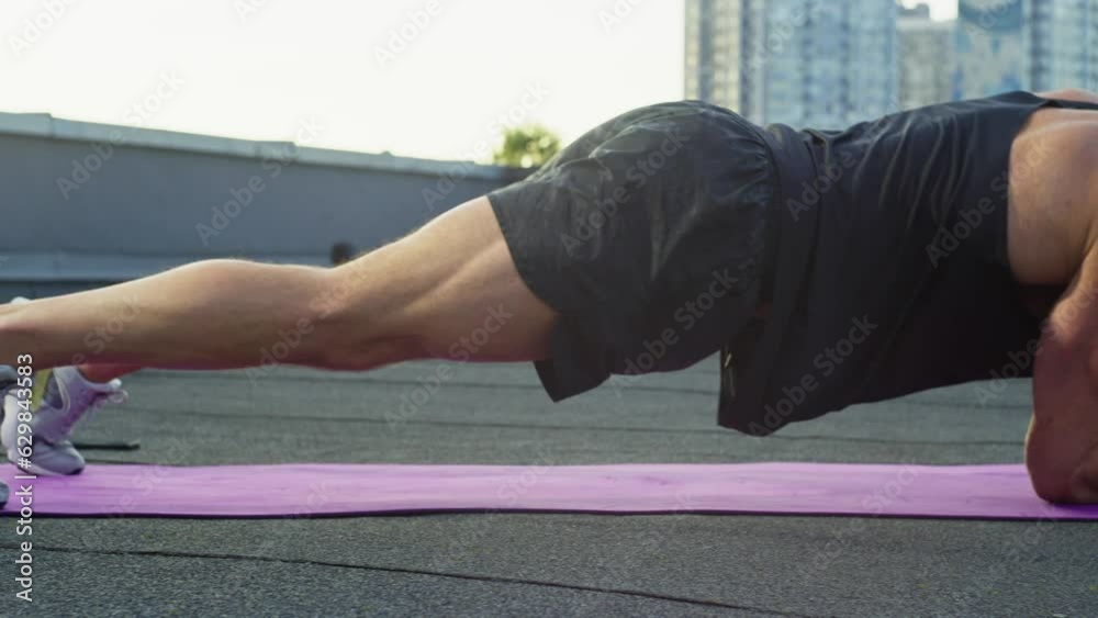 Close-up of an athlete standing in a plank and raising his arms ...