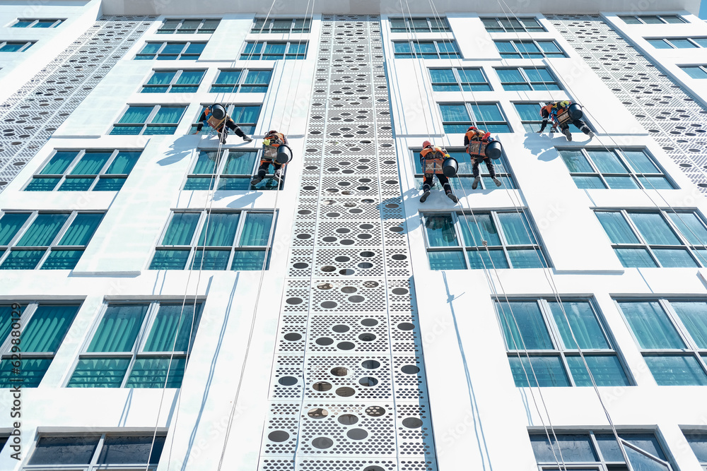 Workers climb high-rise buildings using ropes to clean window panes ...