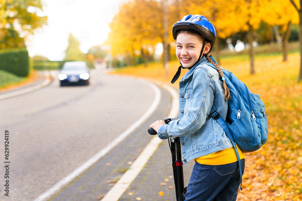Road to school. Happy kid riding scooter on autumn city street. Child ...