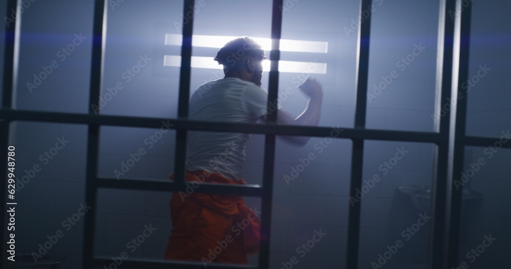 Male African American prisoner in orange uniform does shadow boxing in ...