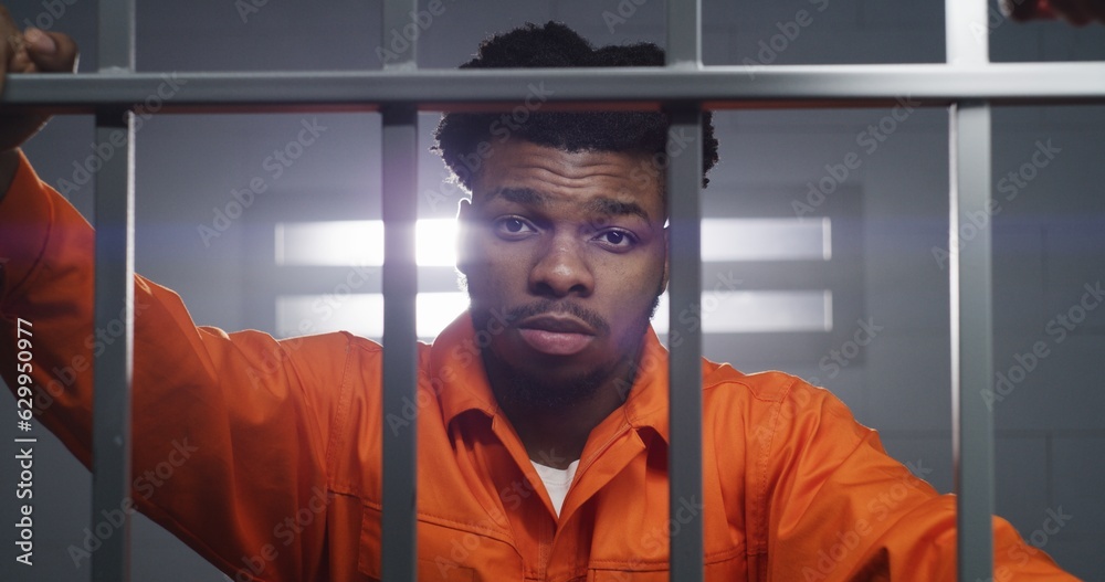 African American Man In Orange Uniform Looks At Camera And Kneads Neck