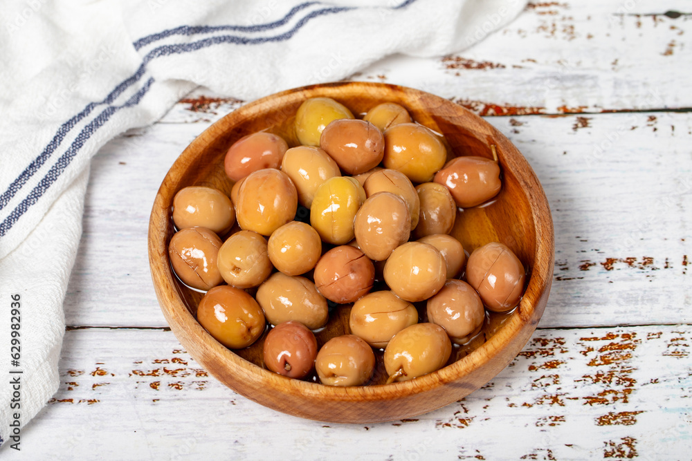 Scratched green olive at wooden bowl. Green olives on a white wood ...