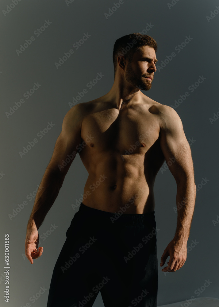 Slim muscular male model at gray background. Fitness shirtless guy in ...
