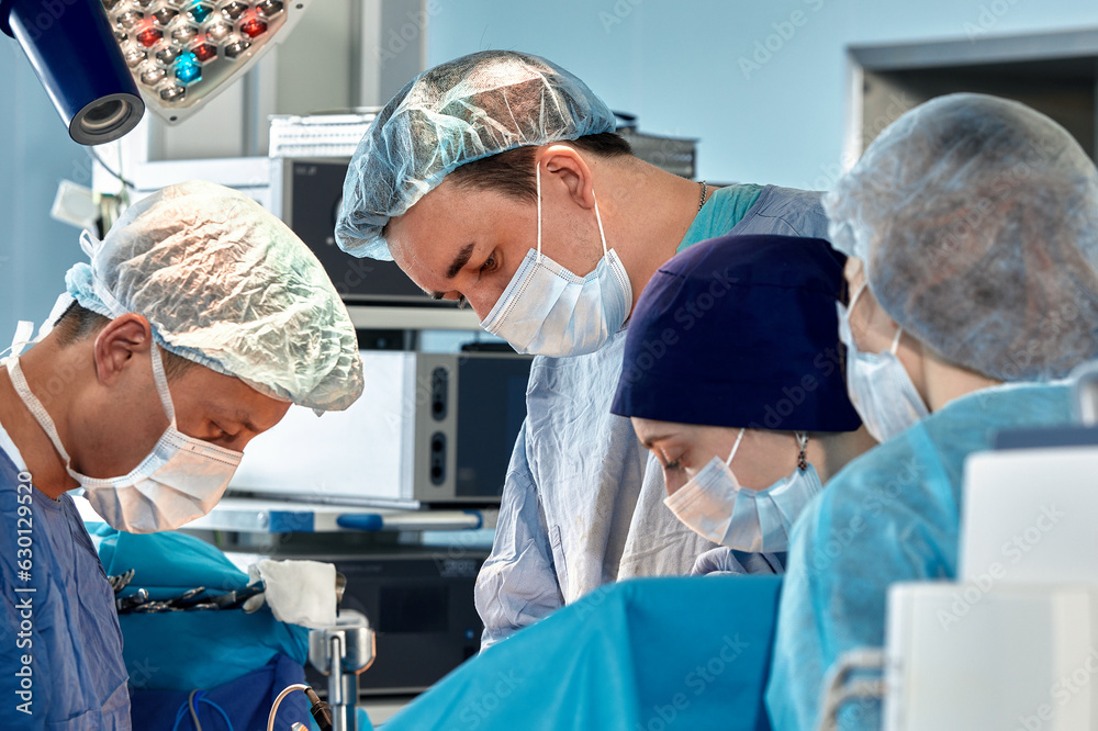 Portrait of surgeons leaned over patient during complex surgical ...
