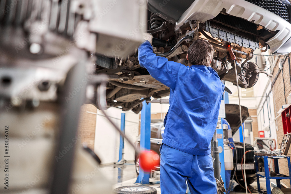 Car mechanic inspecting car steering rod and repair suspension detail ...