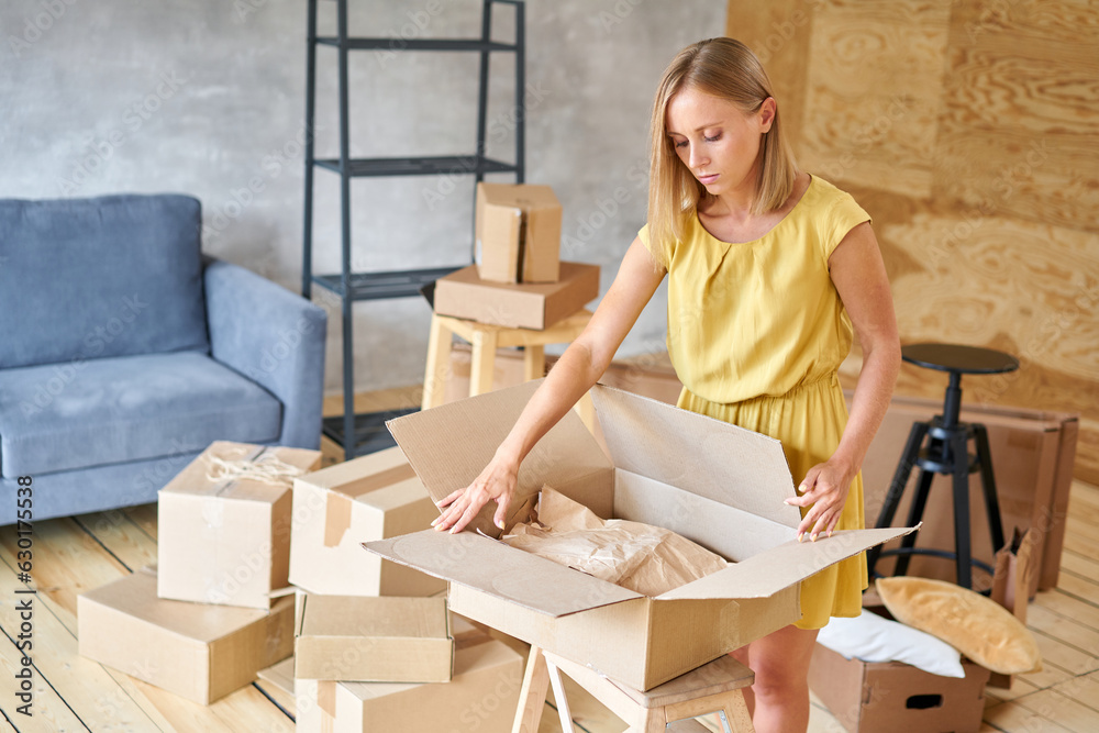 Young girl packing plates into the boxes ready to move. Woman unpacking ...