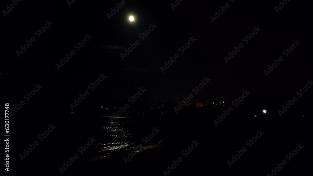 Moon in sky and moonlight path on sea waves on beach of sea coast ...