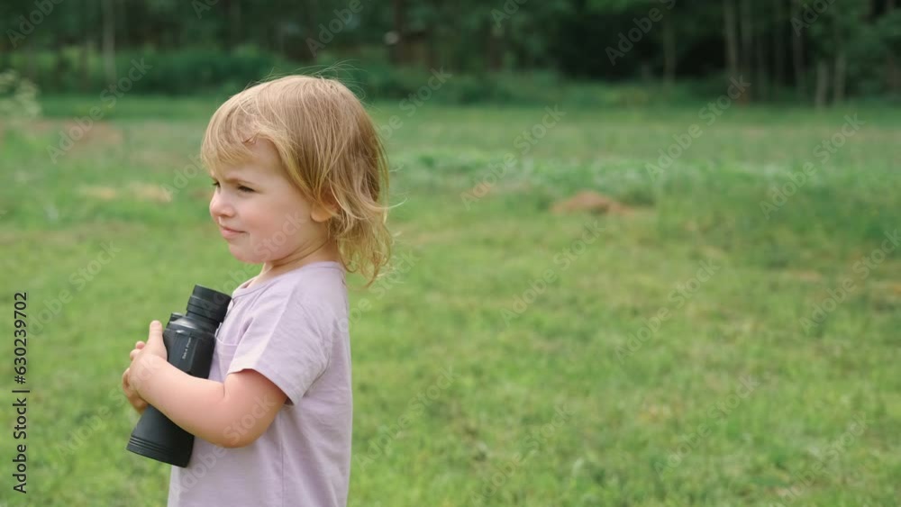 Little girl using binoculars in a forest. 2 years kid looking ahead ...