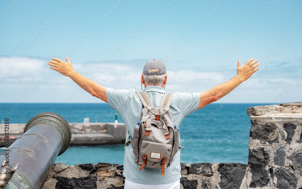 Rear view of senior traveler man in outdoors face to the sea with ...