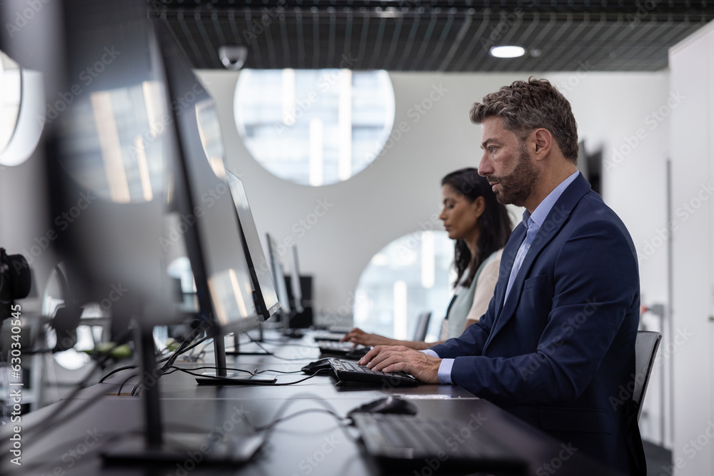 Male business executive working in an office on a desktop computer ...