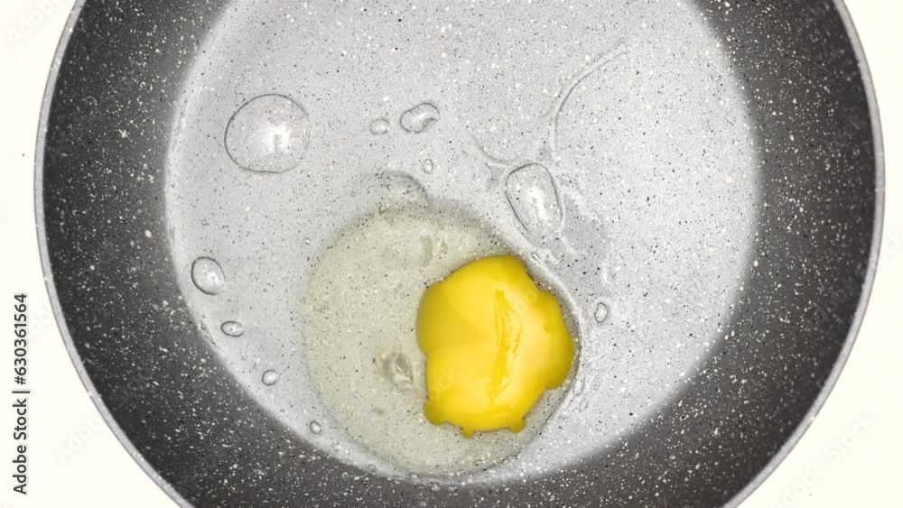woman cracking breaking an egg in frying pan, falling yolk and albumen ...