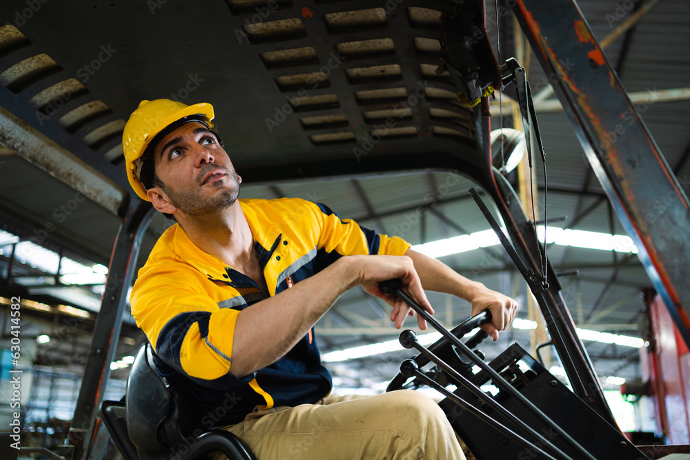 Male factory worker driving and operating a forklift in an industrial ...