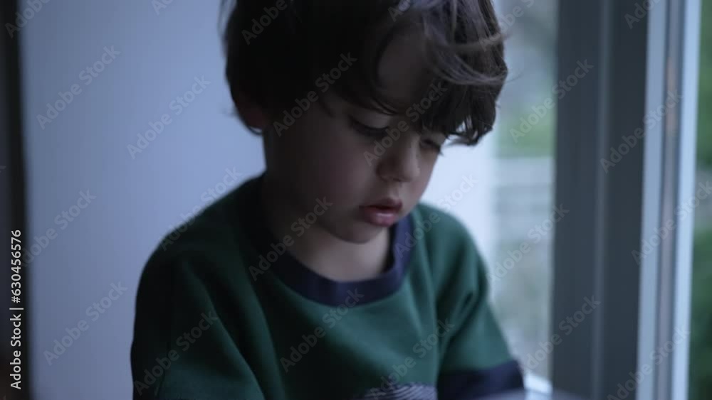 Sad depressed child with melancholic expression looking down with ...