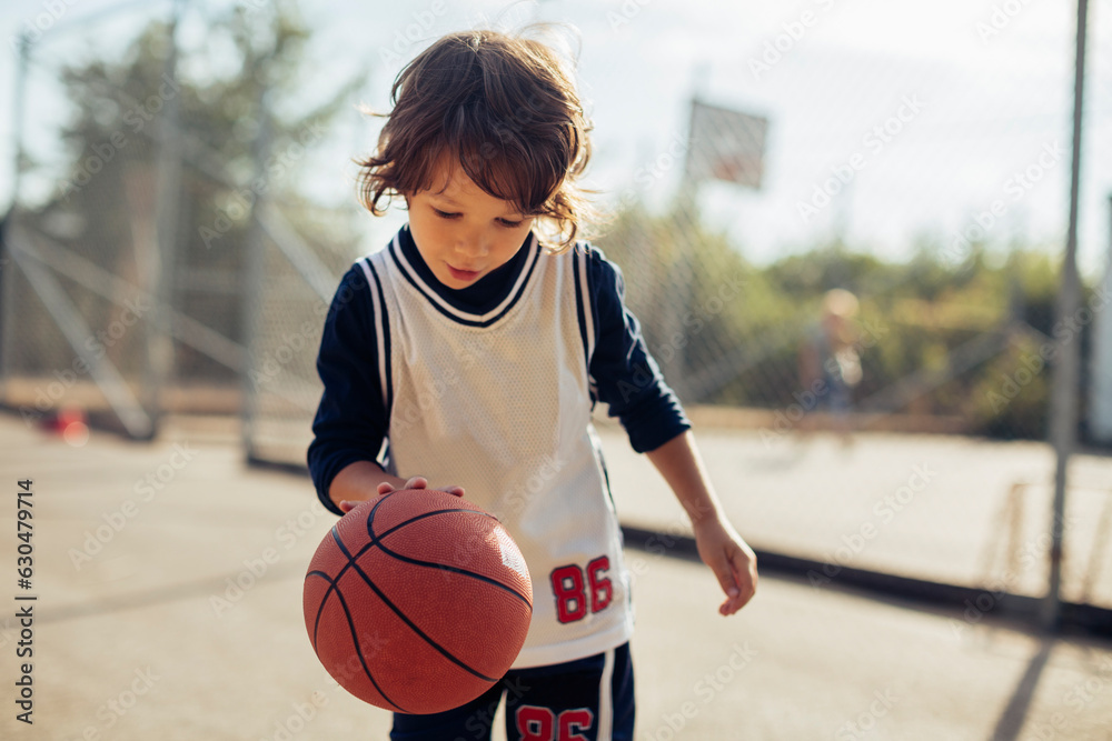 Young boy playing basketball on a basketball court outside in the ...