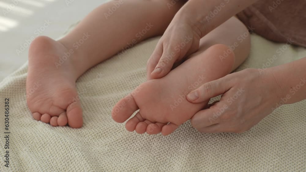 Close-up hands of unrecognizable female pediatric masseuse massaging ...