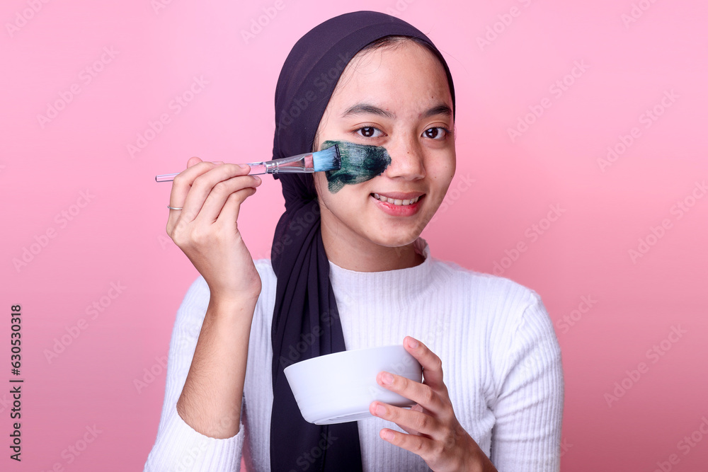 Young Asian beautiful muslim woman applying spirulina mask over pink ...