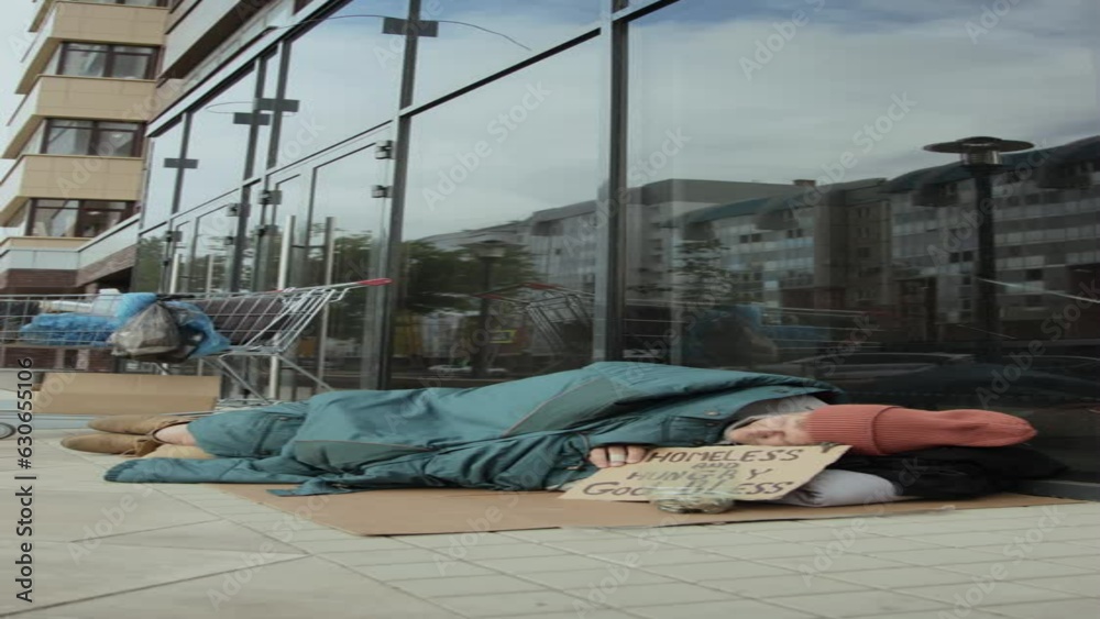 Vertical shot of homeless man with sign sleeping on cardboard sleeping ...