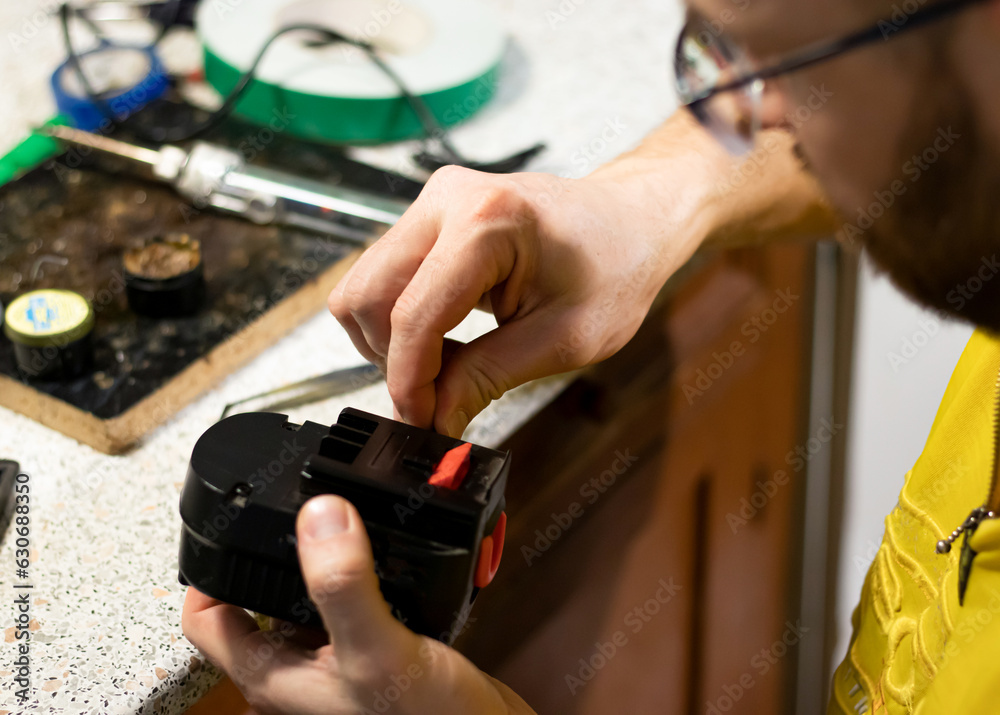 Adult man with glasses is concentrating on repairing a complex battery ...