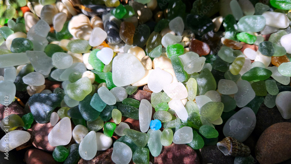 Stones and glass, sea pebbles of different colors in the shade with ...