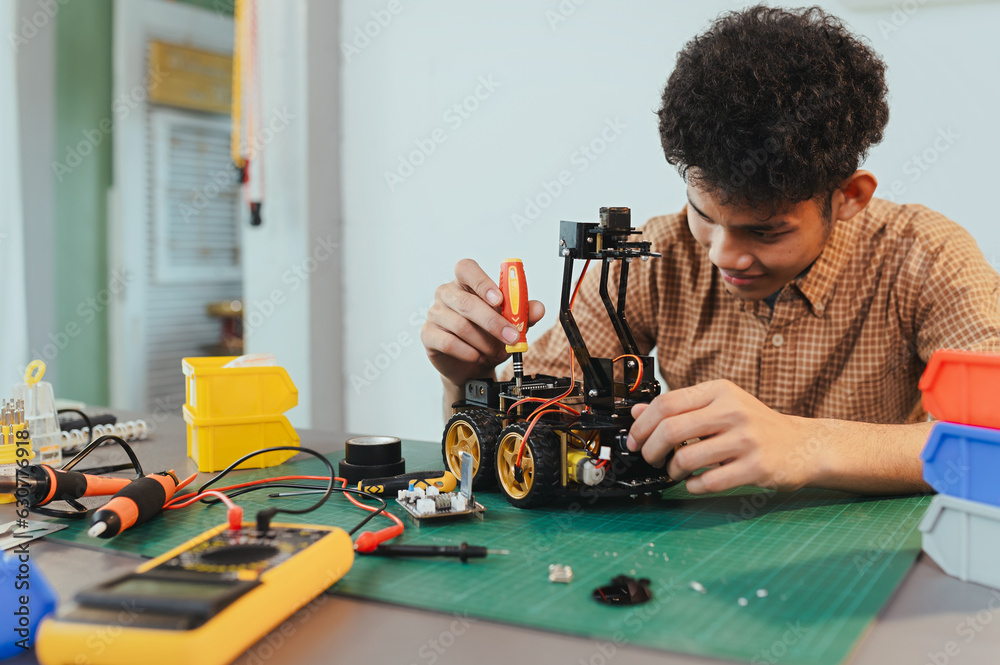 Asian young man assembling a robotic car, focus on robotics, assembling ...