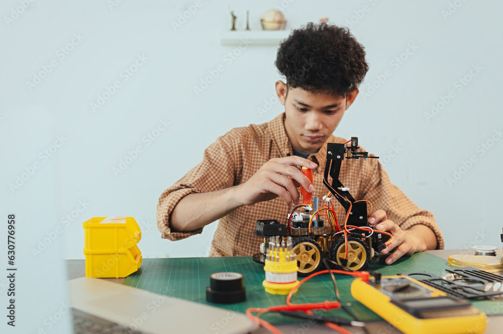 Asian young man assembling a robotic car, focus on robotics, assembling ...
