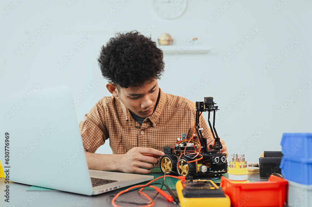 Asian young man assembling a robotic car, focus on robotics, assembling ...