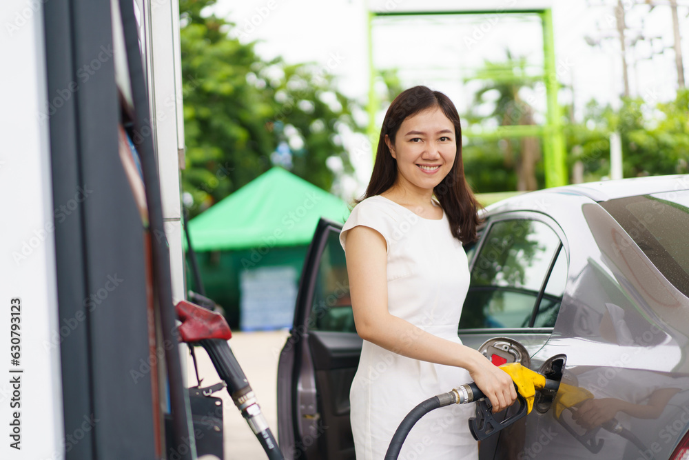 Happy Asian woman refueling a vehicle gas at gas station, self-service at gas station concept ...