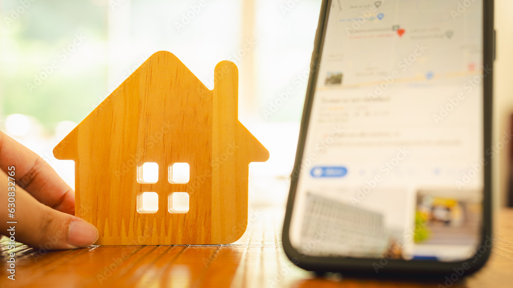 Model of a wooden house with a mobile phone showing the location of the ...