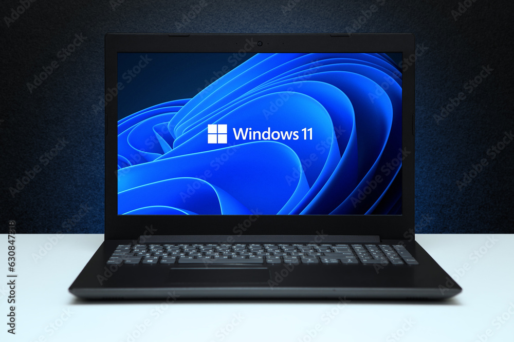 Windows 11 logo on the screen laptop computer on black textured wall ...