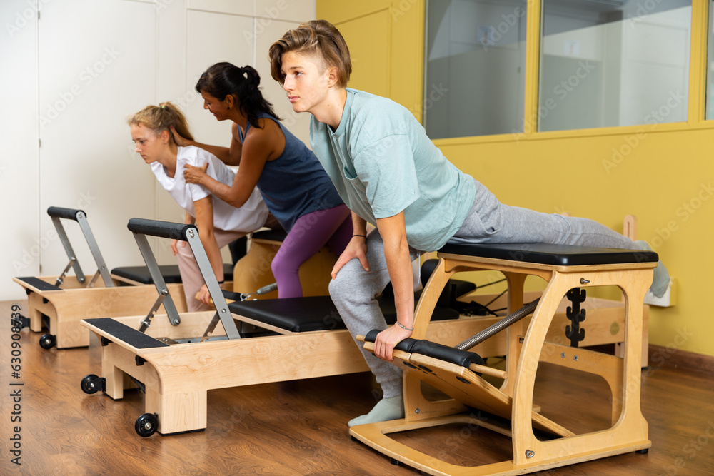 Teen boy and girl in sportswear keeps the balance, pilates training on ...