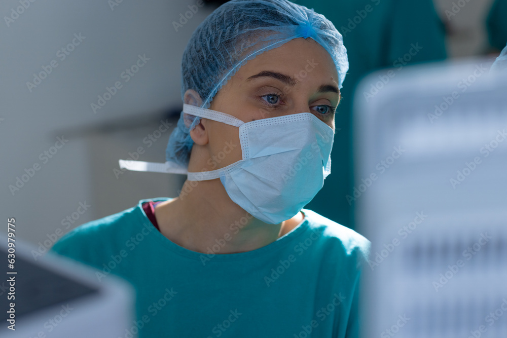 Caucasian female surgeon wearing surgical gown and face mask in ...