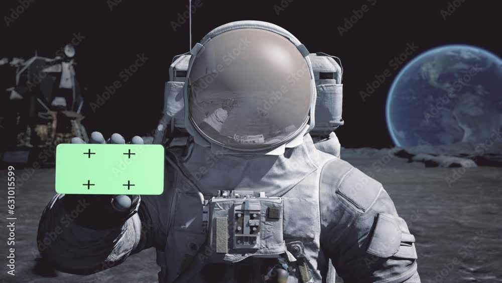 Astronaut on Moon wearing helmet shows a smartphone with a green screen ...