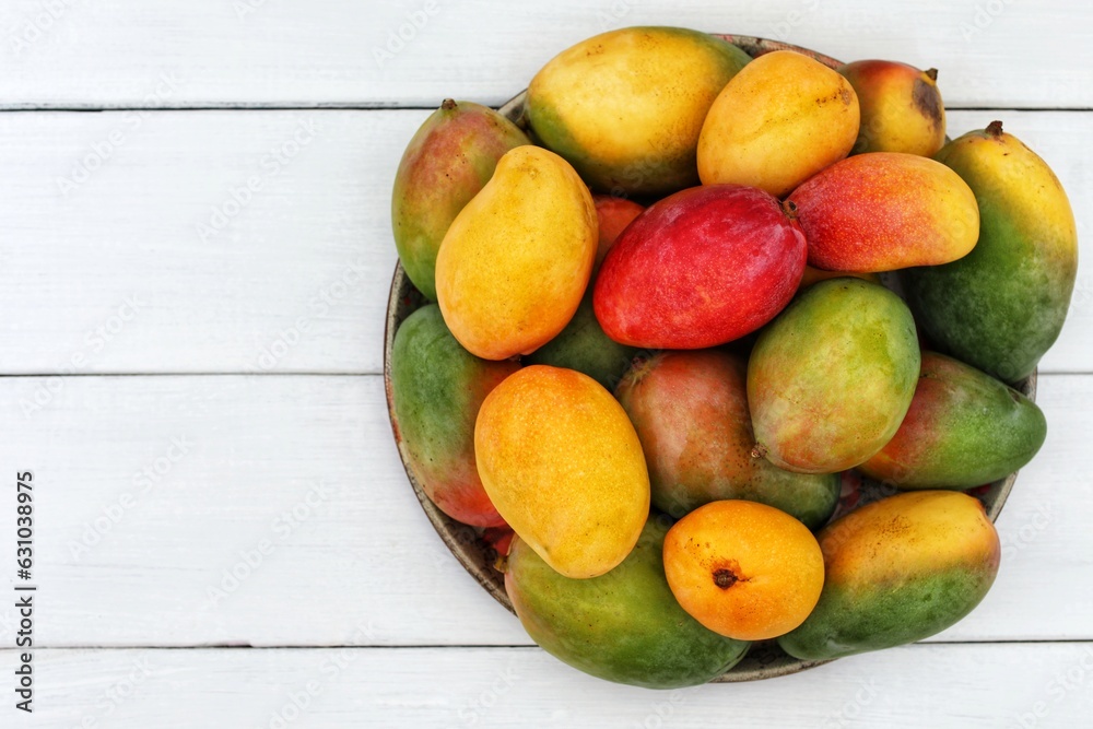Many mangoes on the table, exotic fruits, wooden background, top view ...