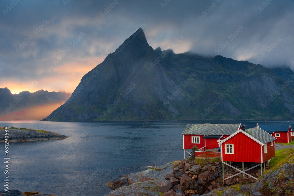 Amazing sunset through the mist and the Reinebringen Mount over the red houses of Hamnoy ...