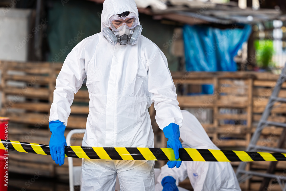 A team of two chemists, wearing PPE suits and gas masks, recover a ...