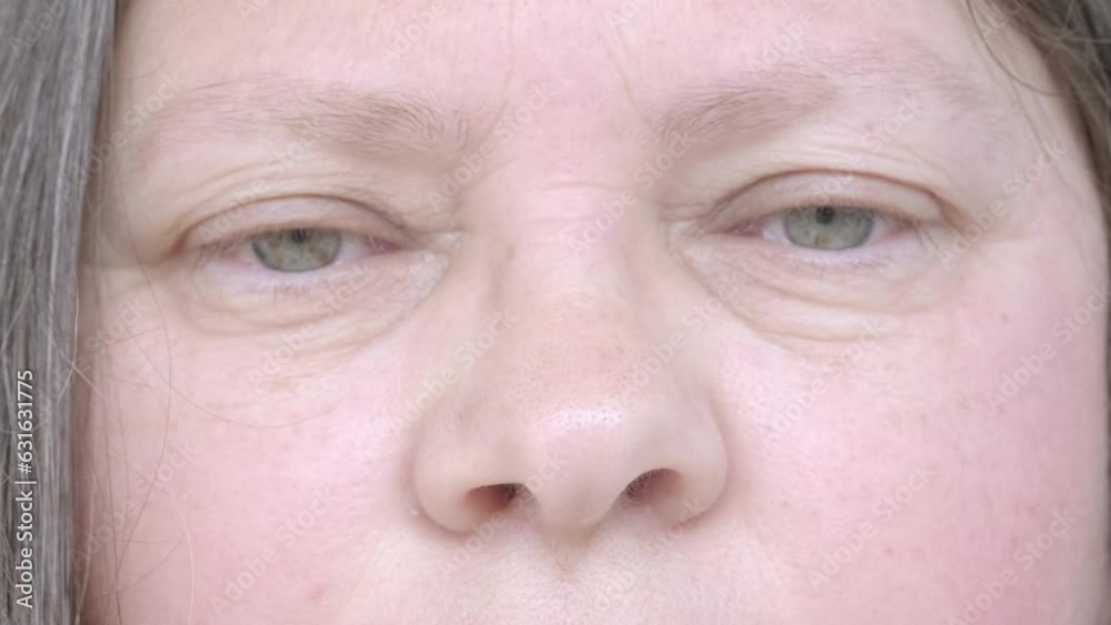 close-up of mature woman 50 years old looks carefully swelling under ...