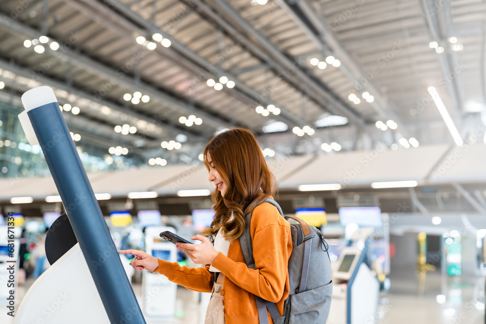 Young Asian woman using self check-in kiosks in airport terminal. Happy ...
