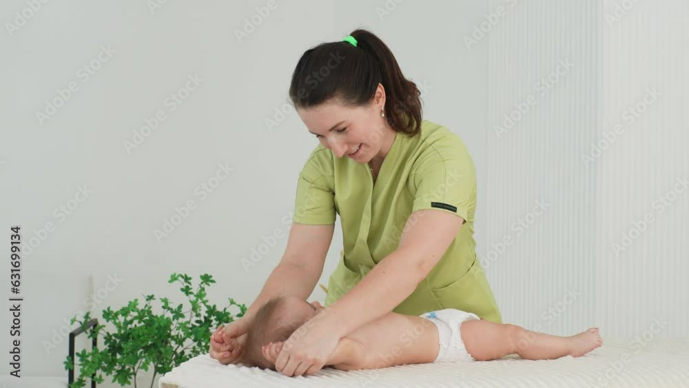 Portrait of smiling pediatric masseur with cute baby boy doing exercise ...