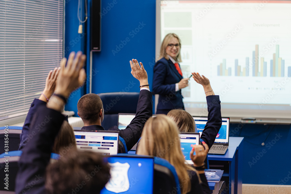 Students raising their hands while their professor is giving a lecture ...